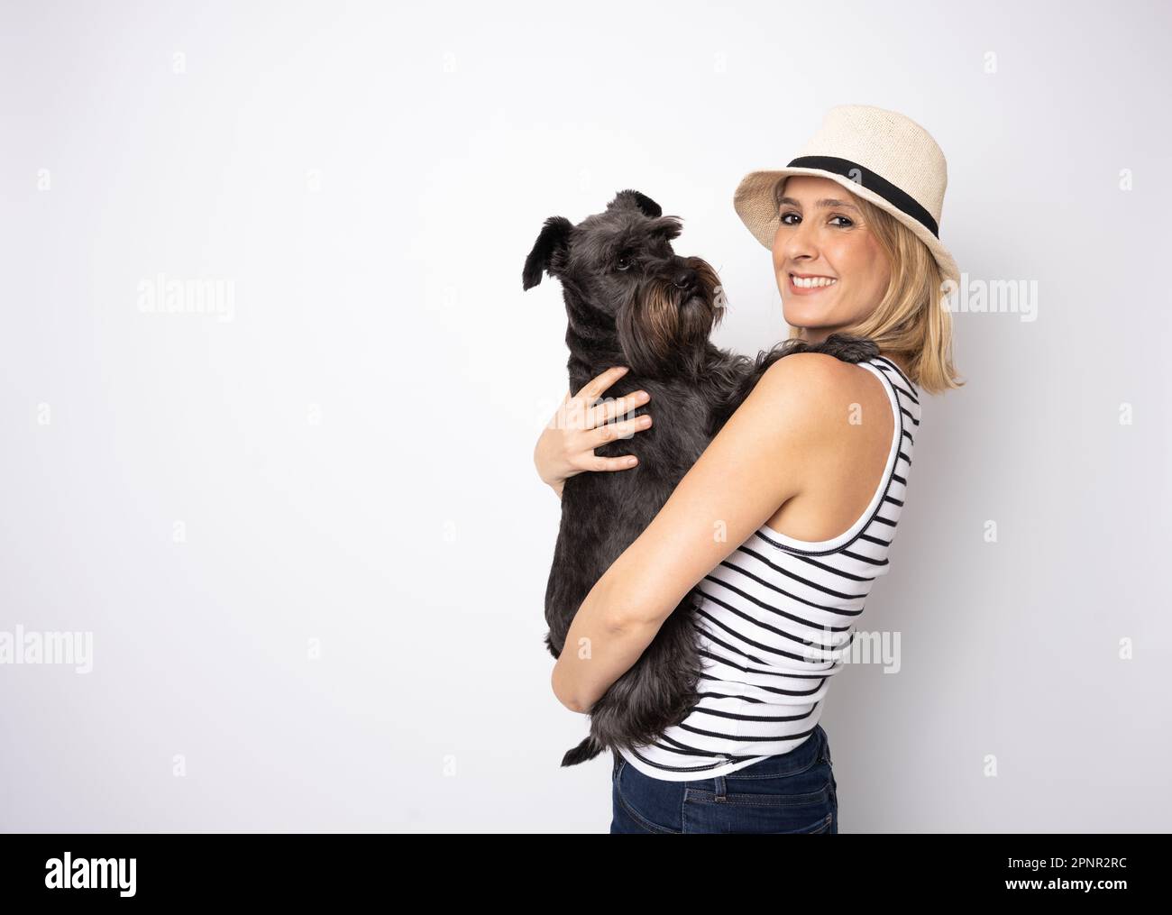 Cute young woman hugs her puppy schnauzer dog. Love between owner and ...