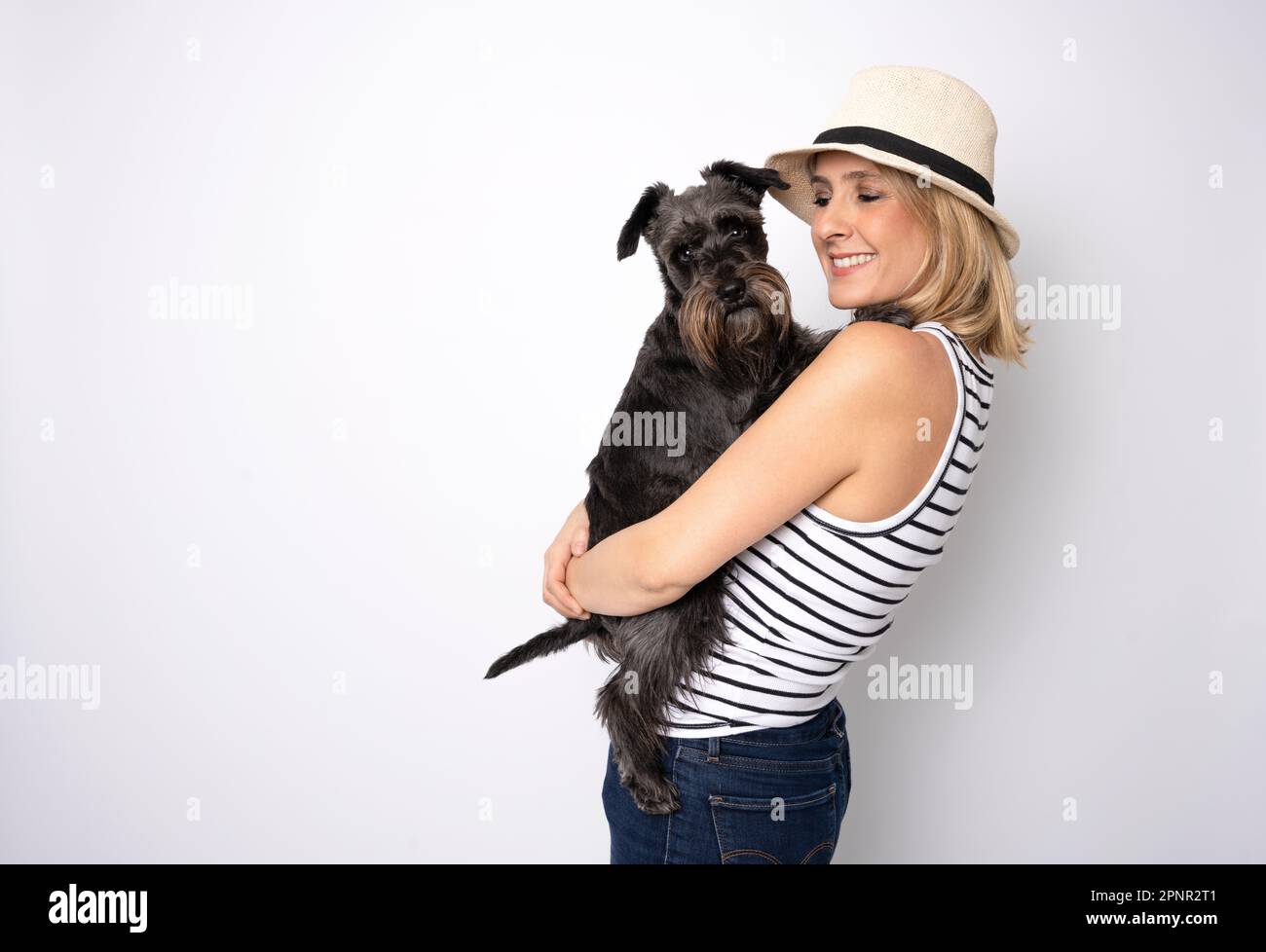 Cute young woman hugs her puppy schnauzer dog. Love between owner and ...