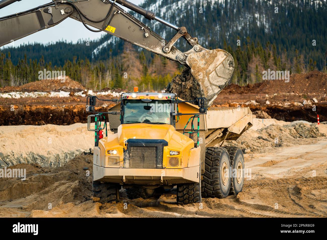 Loading dirt into a dumper using an excavator at a construction site in ...