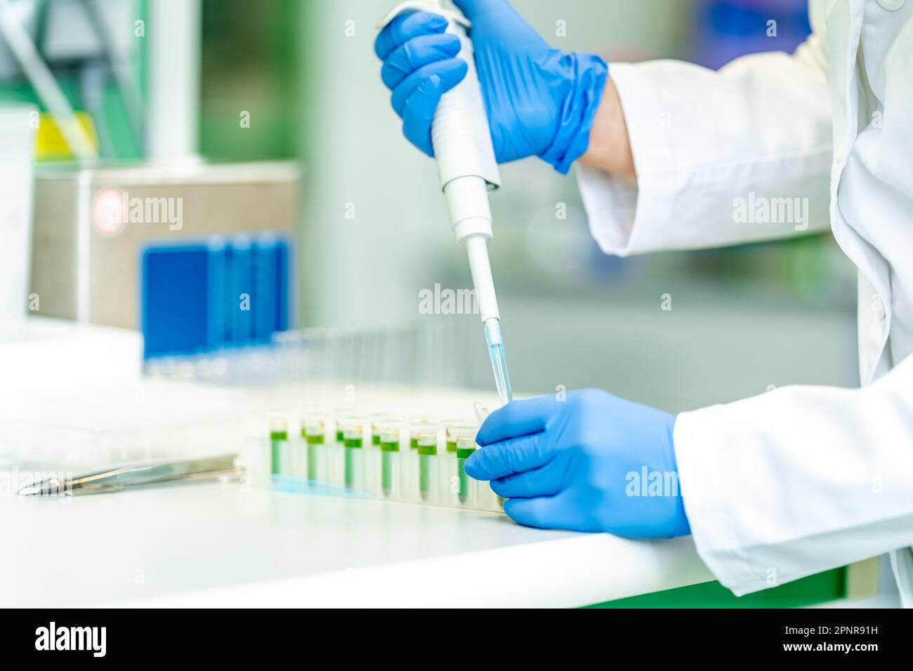 pipetting a sample into a glass beaker during research in a scientific ...