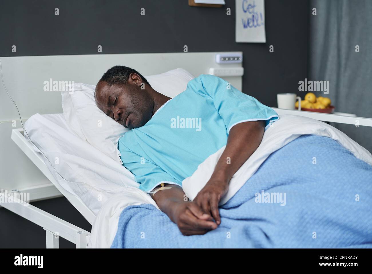 African American man resting on bed in ward during his rehablitation in ...