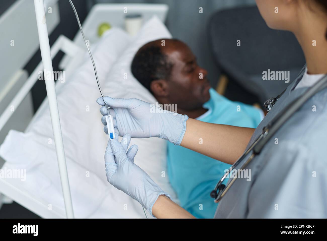 Close-up of nurse making dropper for patient standing in hospital ward ...