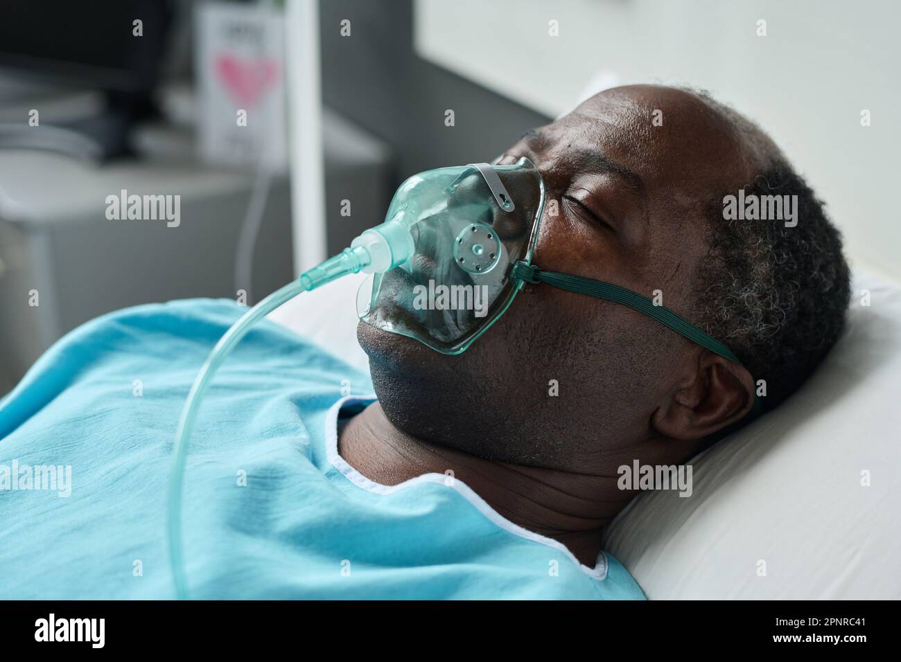 African American elderly man breathing with oxygen mask while lying in ...