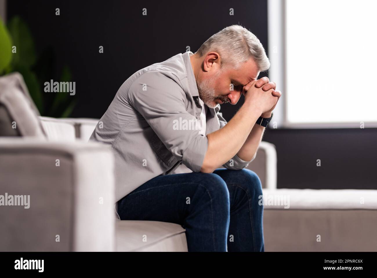 Frustrated middle aged man sitting on couch at home. Close up face of ...