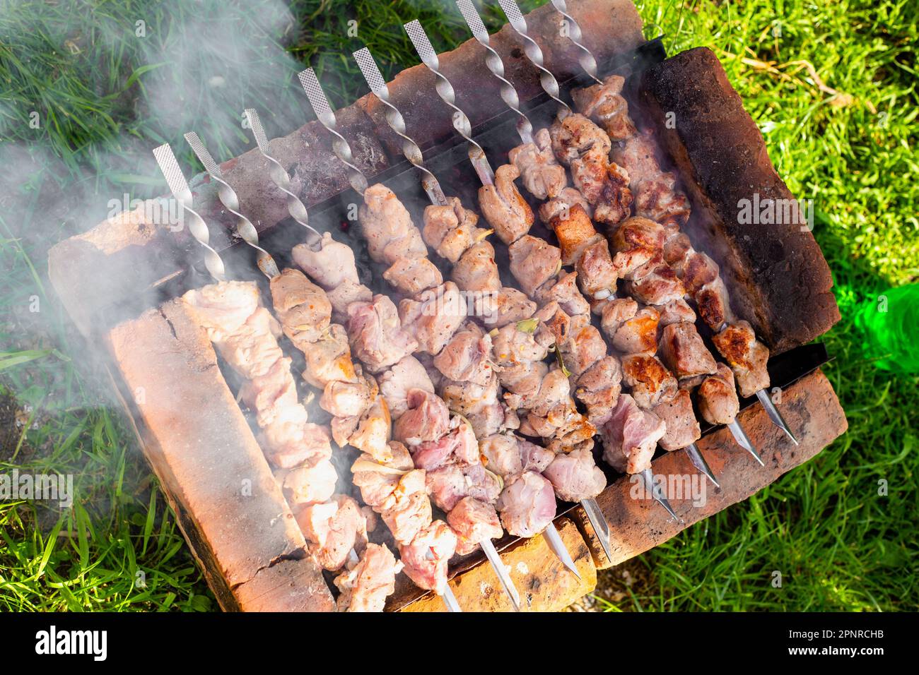 juicy pieces of pork meat are skewered and baked on a homemade brick ...