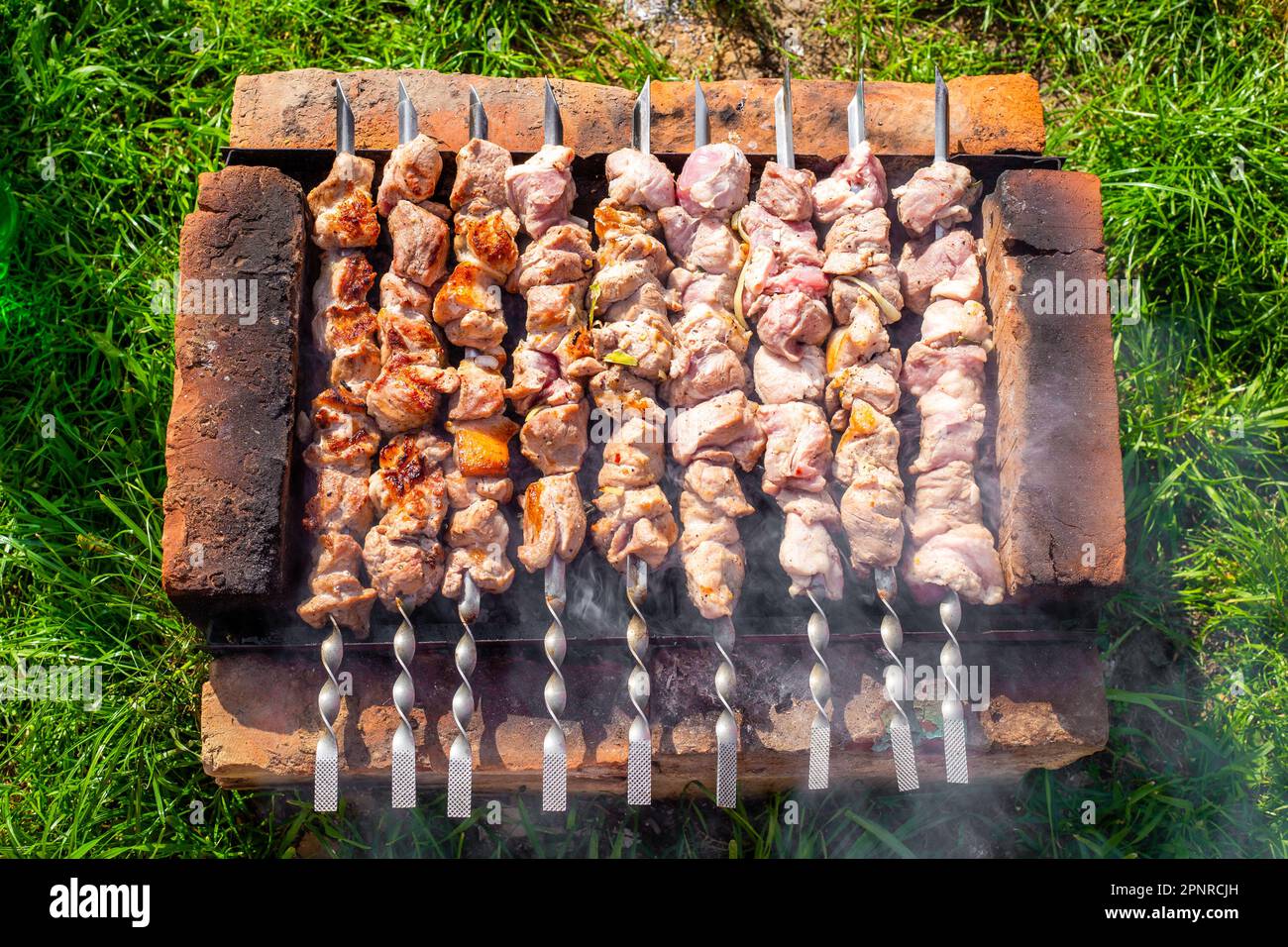 juicy pieces of pork meat are skewered and baked on a homemade brick ...