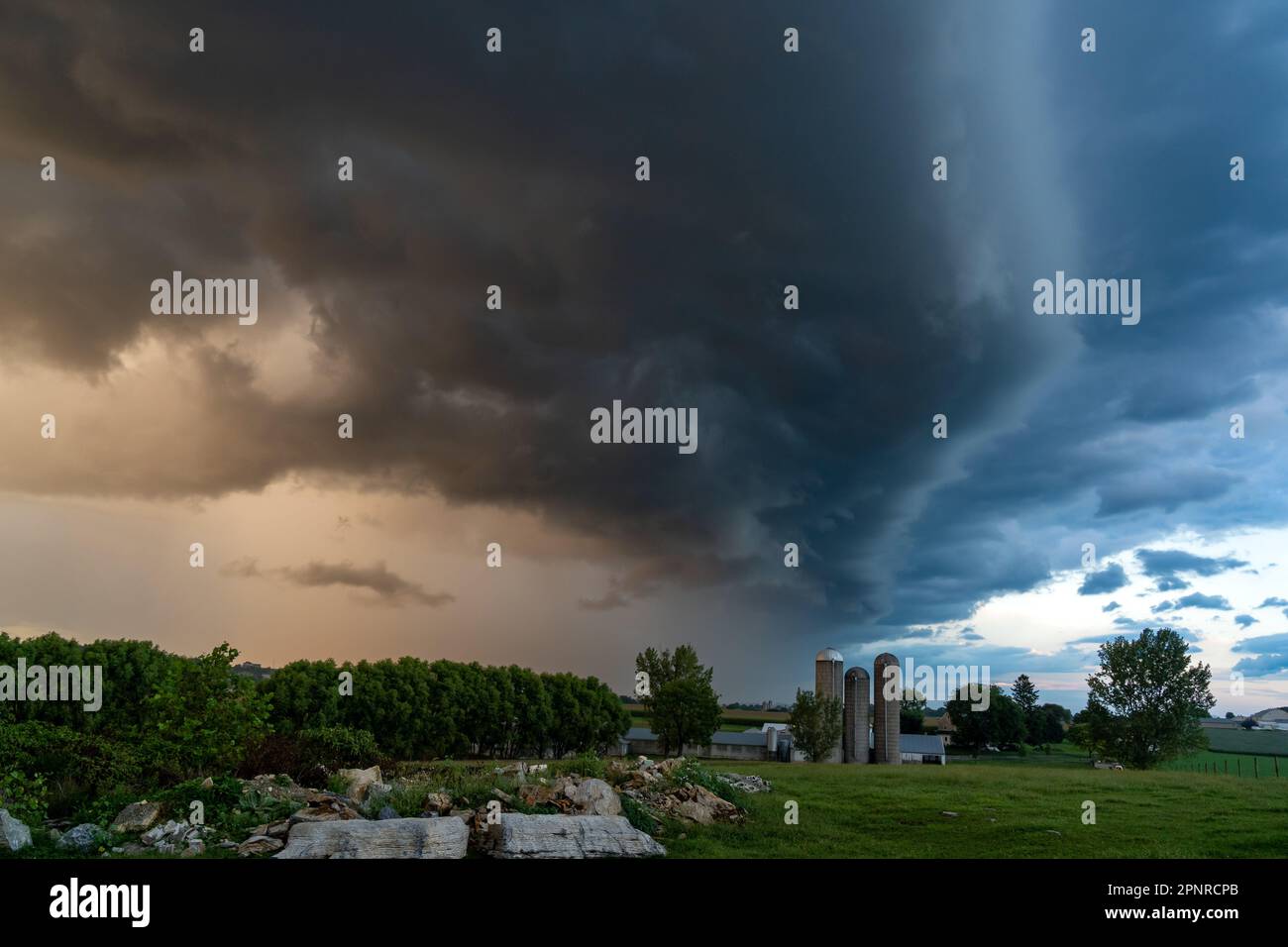 A terrible looking storm over a farm and the lush green farmland of the ...