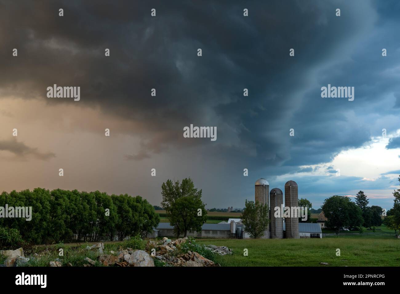 A terrible looking storm over a farm and the lush green farmland of the ...
