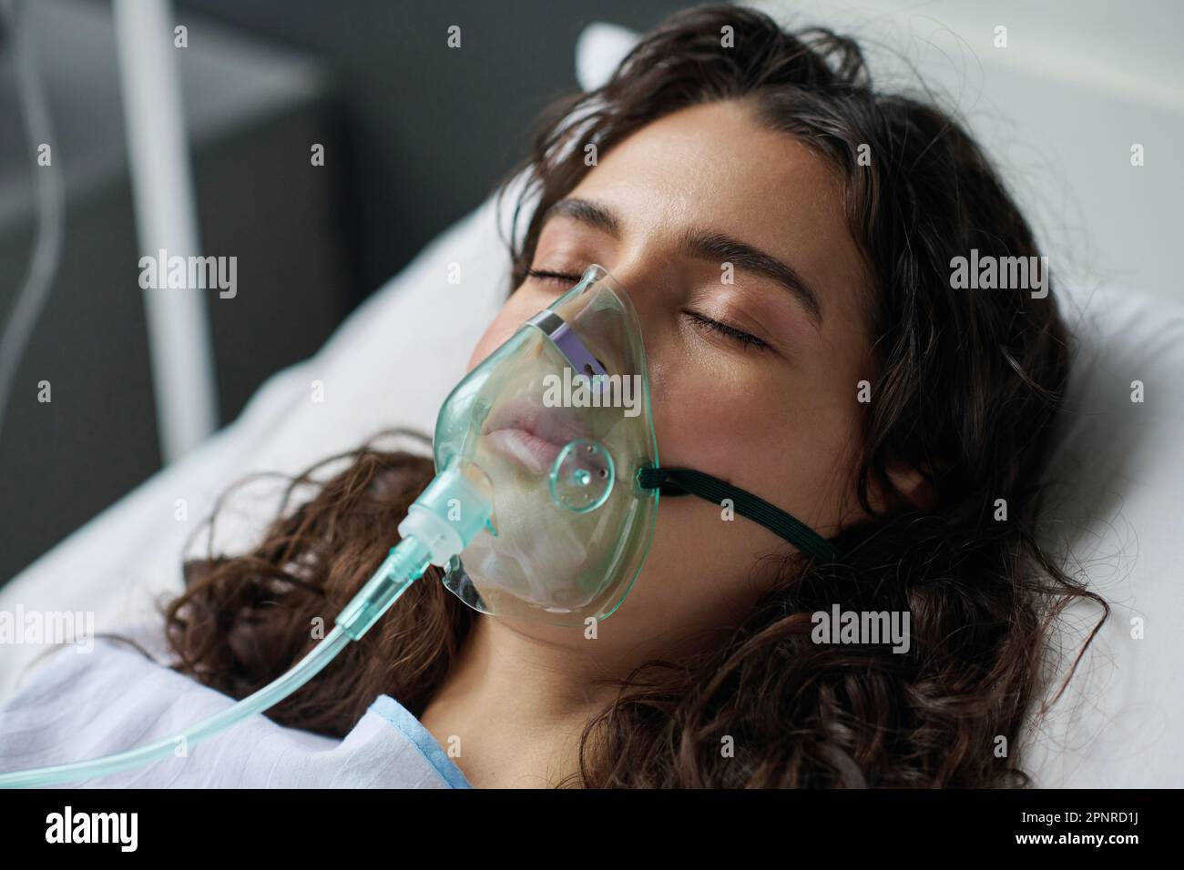 Close-up of young woman lying on bed with her eyes closed and breathing ...