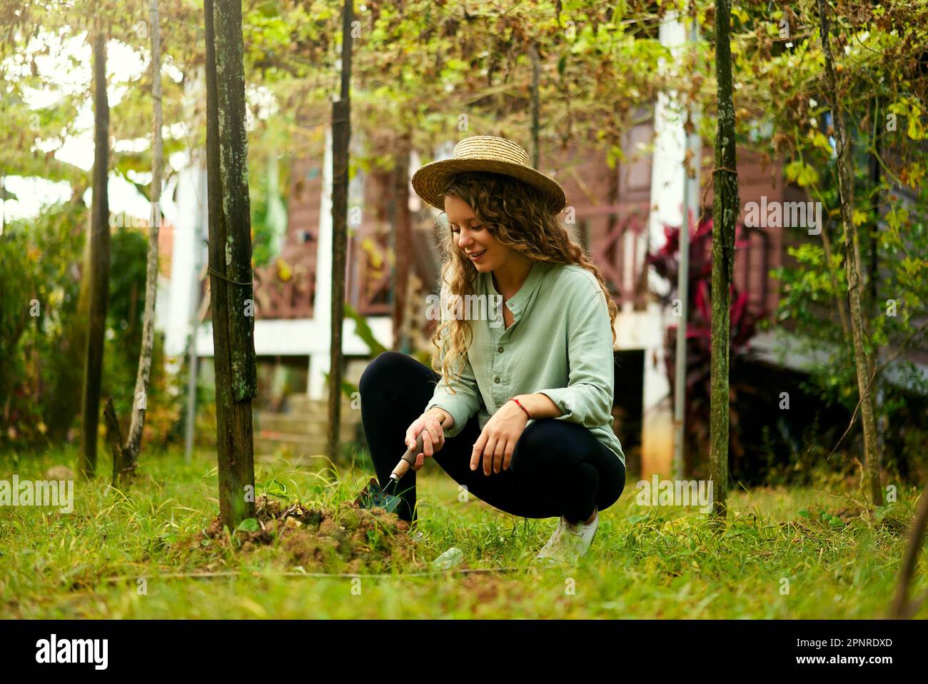 Young caucasian female farmer loosening the soil with garden shovel ...