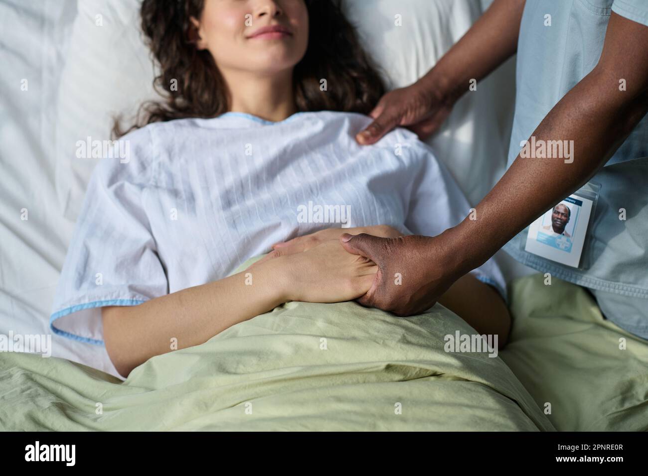 Close-up of male nurse holding hands with patient and supporting her ...