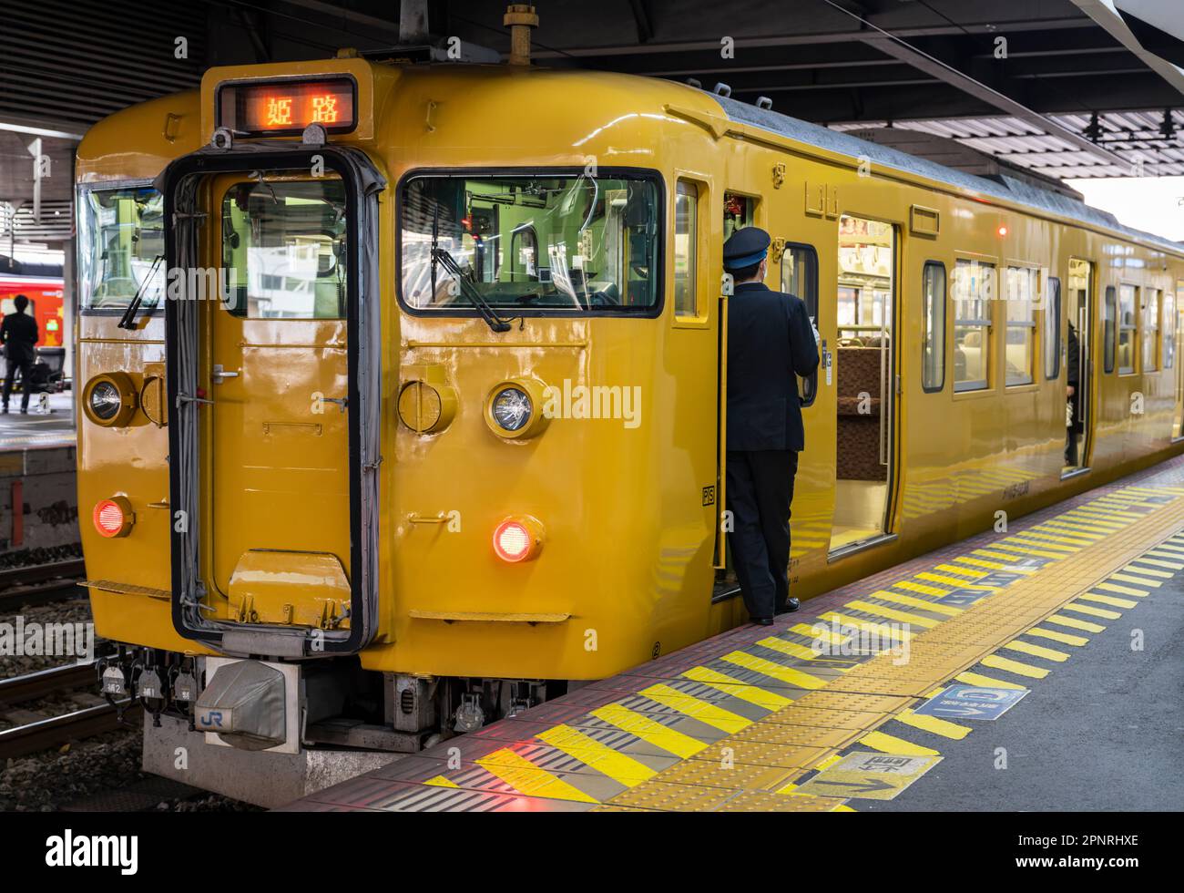 A yellow JR West 115 series train bound for Himeji at Okayama Station ...