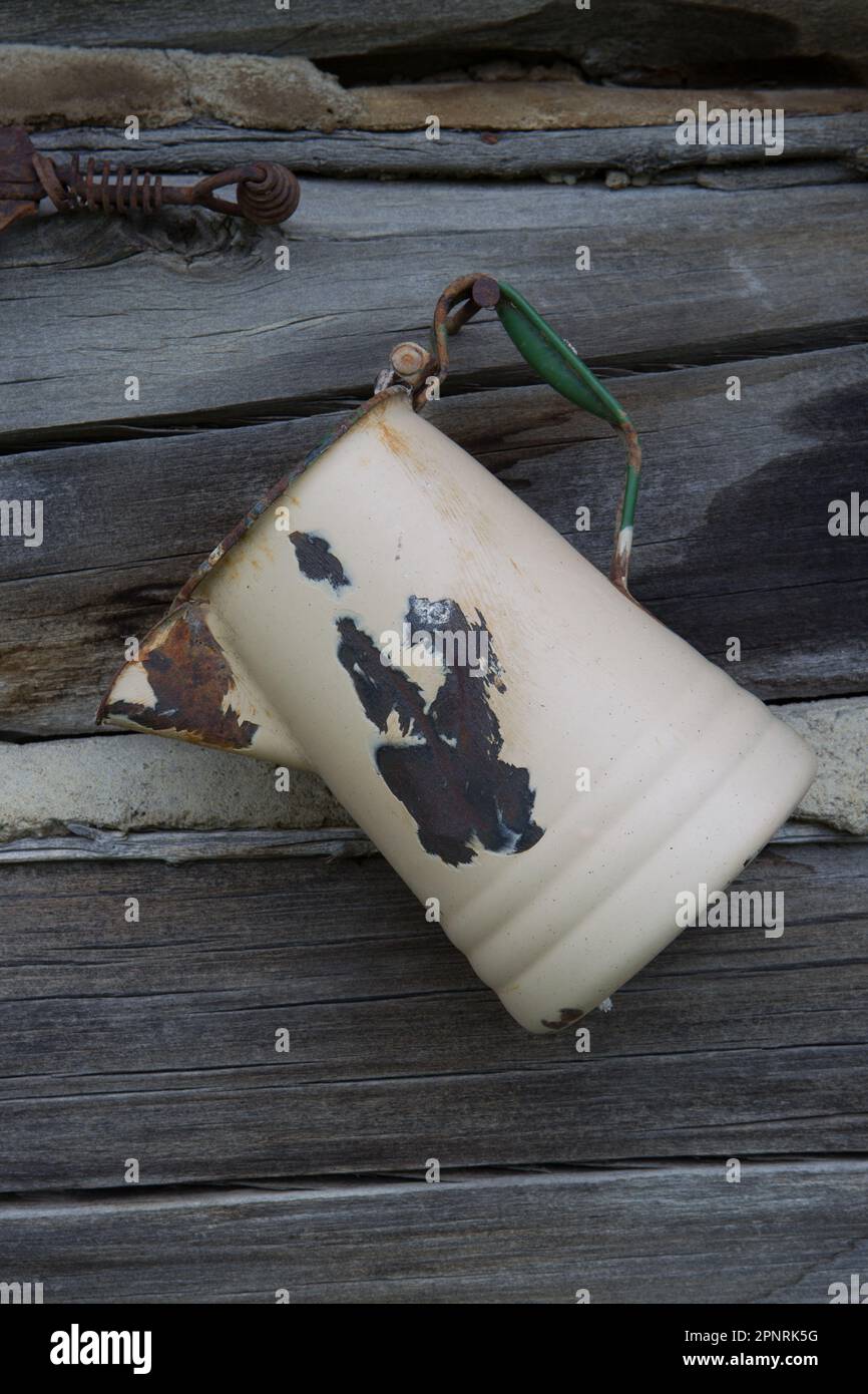 An old rusty, dented porcelain coffee pot hangs on the wall of a ...