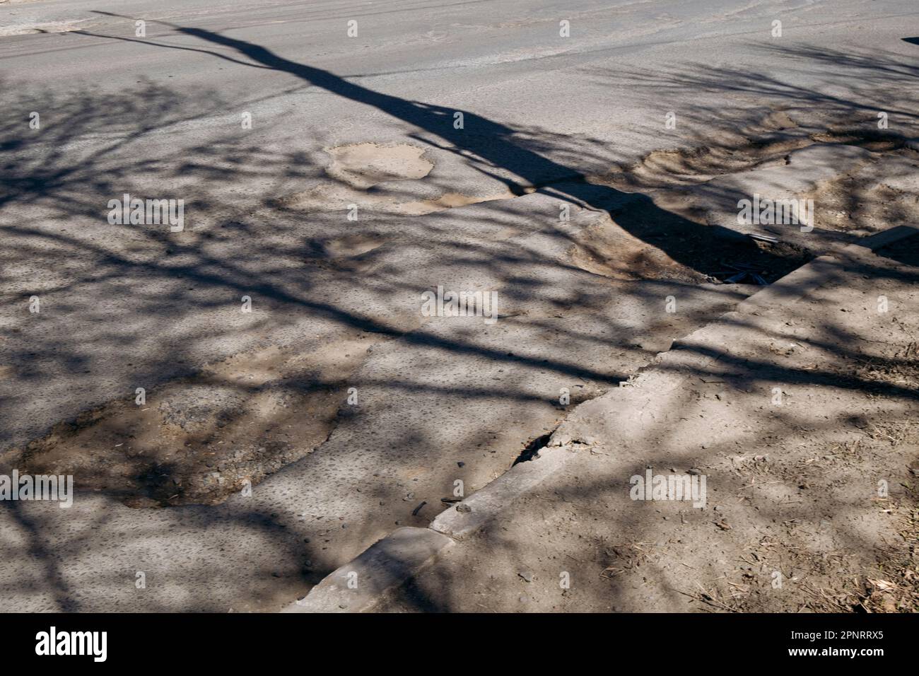 A highway with large pits and shadows from trees Stock Photo - Alamy