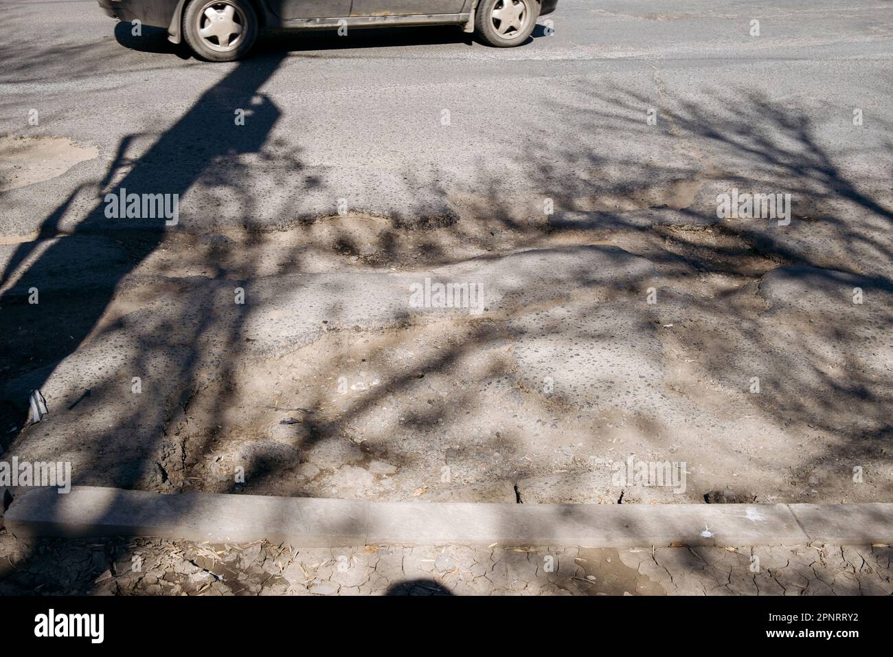 A highway with large pits and shadows from trees Stock Photo - Alamy