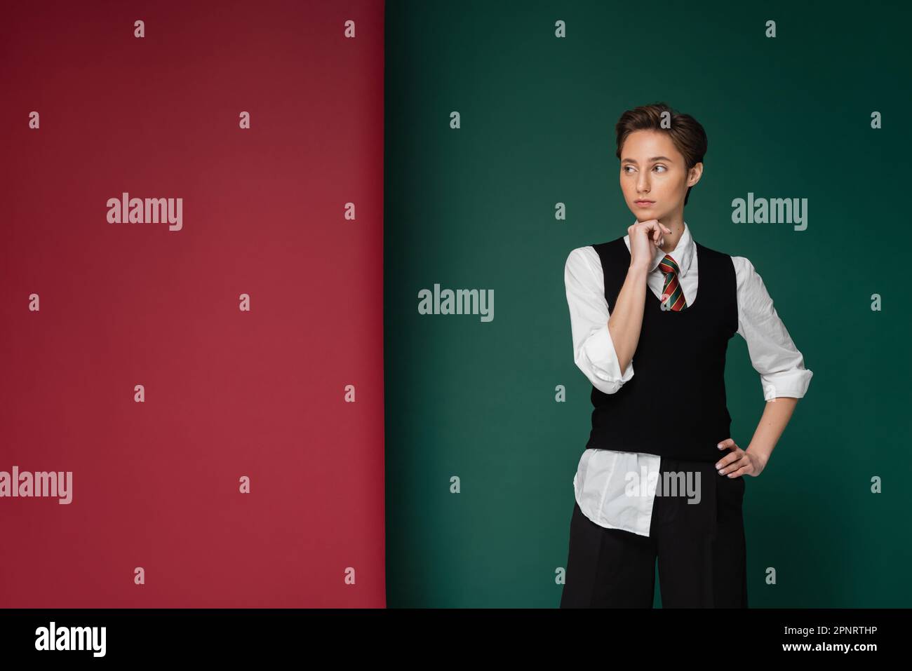 stylish young student with short hair posing with hand on hip on green ...