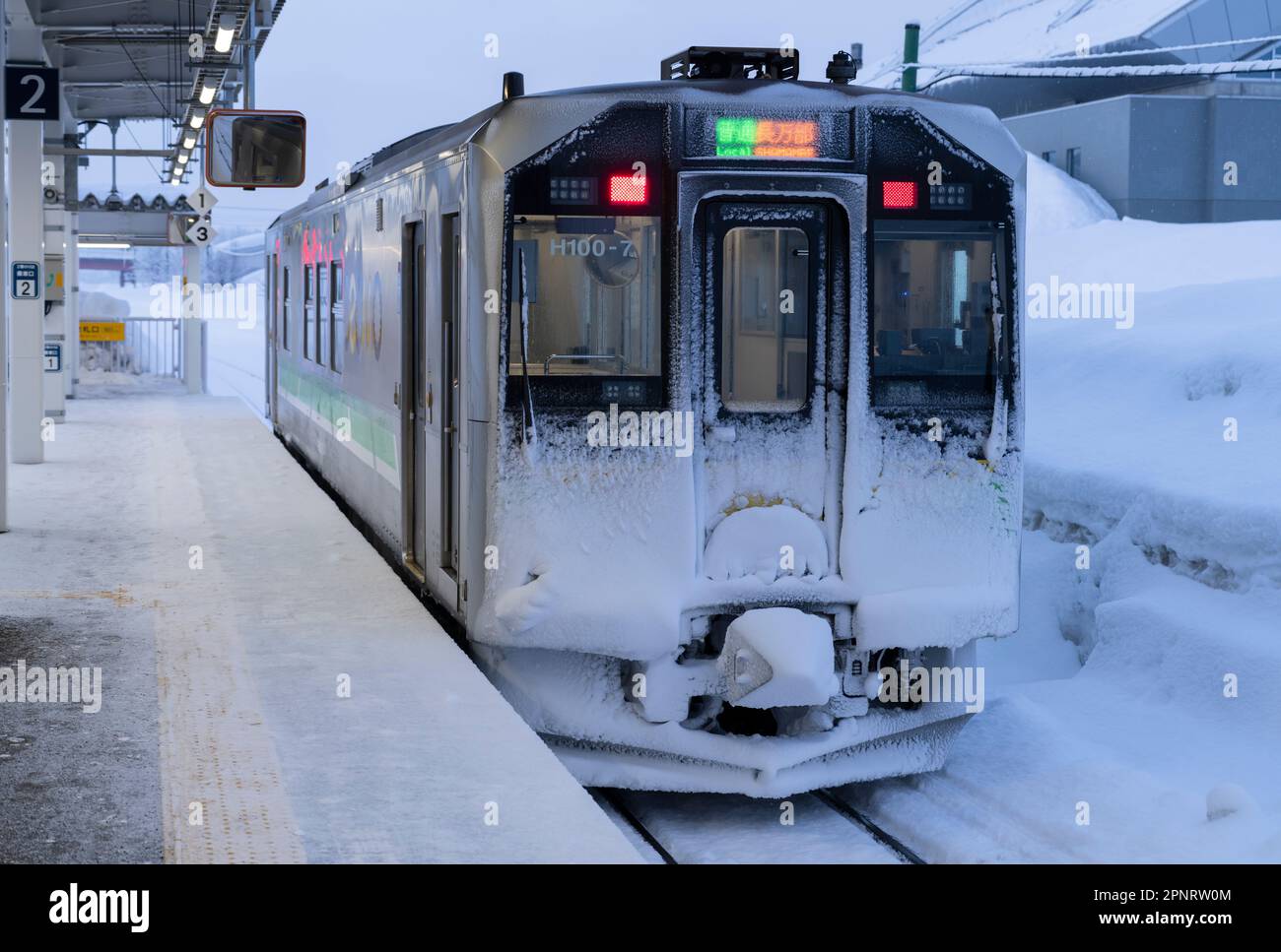 A JR Hokkaido H100 series train on a snowy day at Kutchan Station in ...