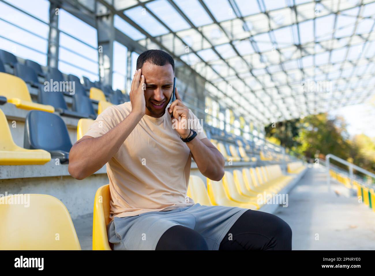Head injury in sports. Young hispanic male postman sits in the stadium ...