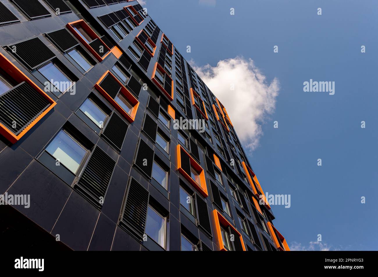 Modern black and orange building against a blue sky, looking up Stock ...
