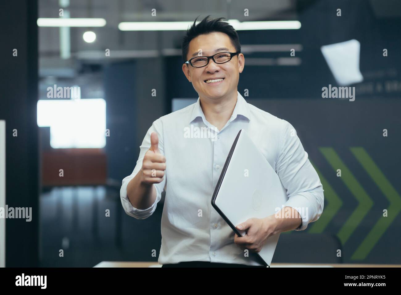 Portrait of a successful young Asian male programmer standing in a ...