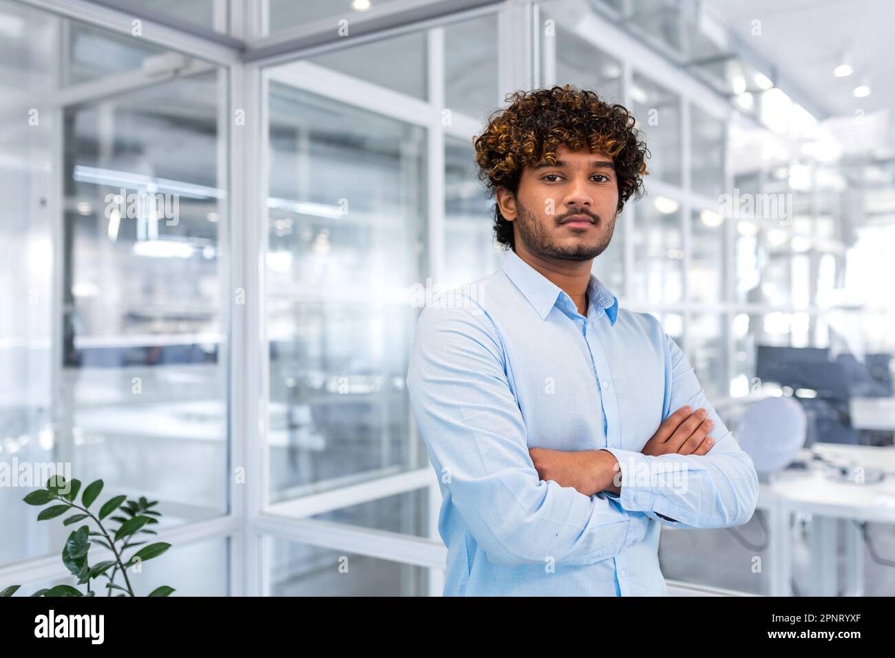 Portrait of a successful young hispanic programmer standing in a modern ...