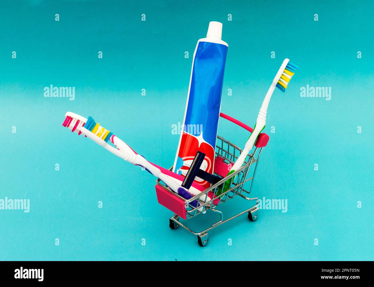 Colorful toothbrushes and toothpaste in a shopping cart on a blue ...