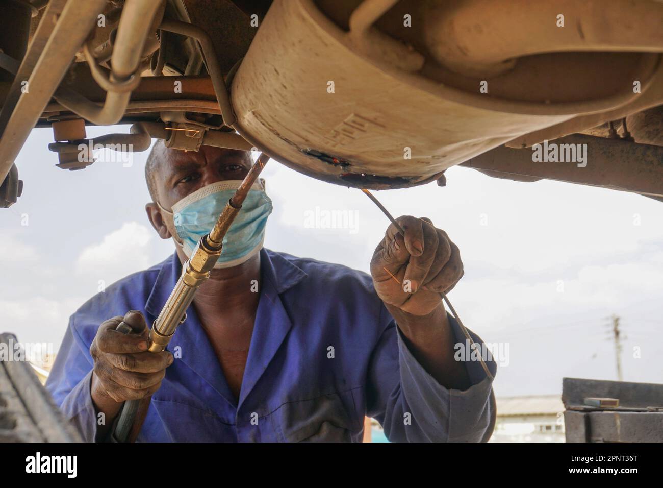 Kennedy Maromo repairs a car’s exhaust pipe in an industrial area in ...