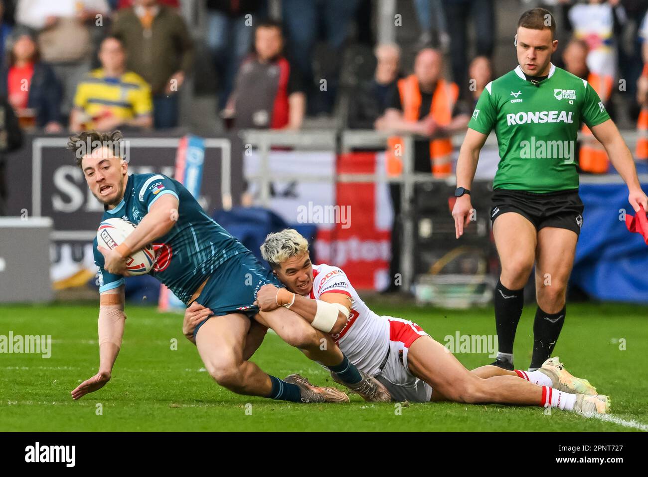 Matty Ashton #5 of Warrington Wolves is tackled by Tee Ritson #25 of St ...