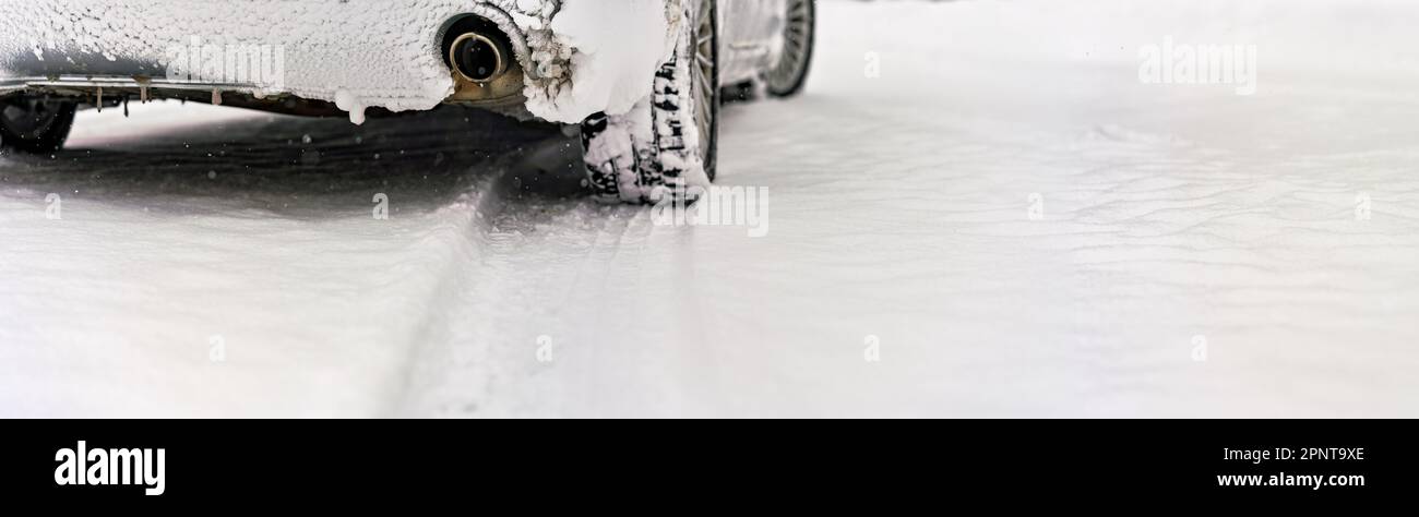 Silver car covered with ice parked on snow covered road, detail view to ...