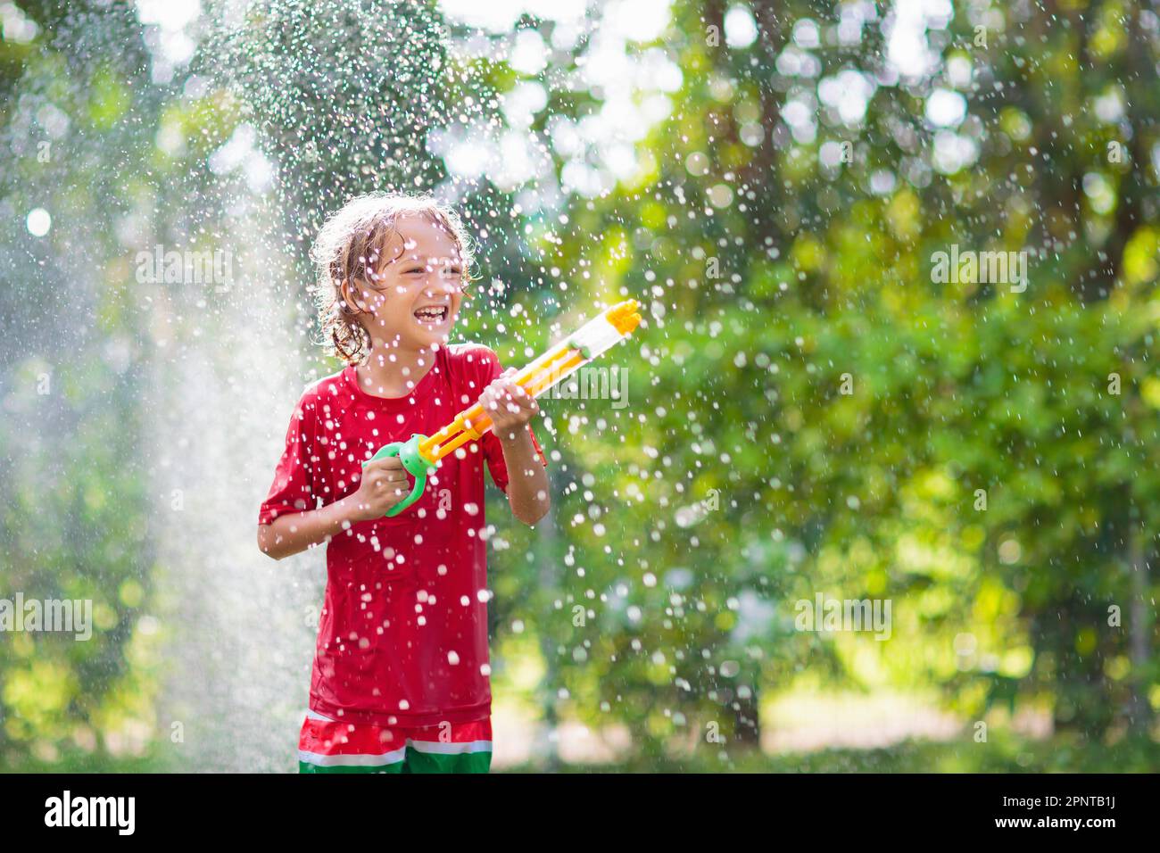 Kids play with water sprinkle hose. Summer garden outdoor fun for ...