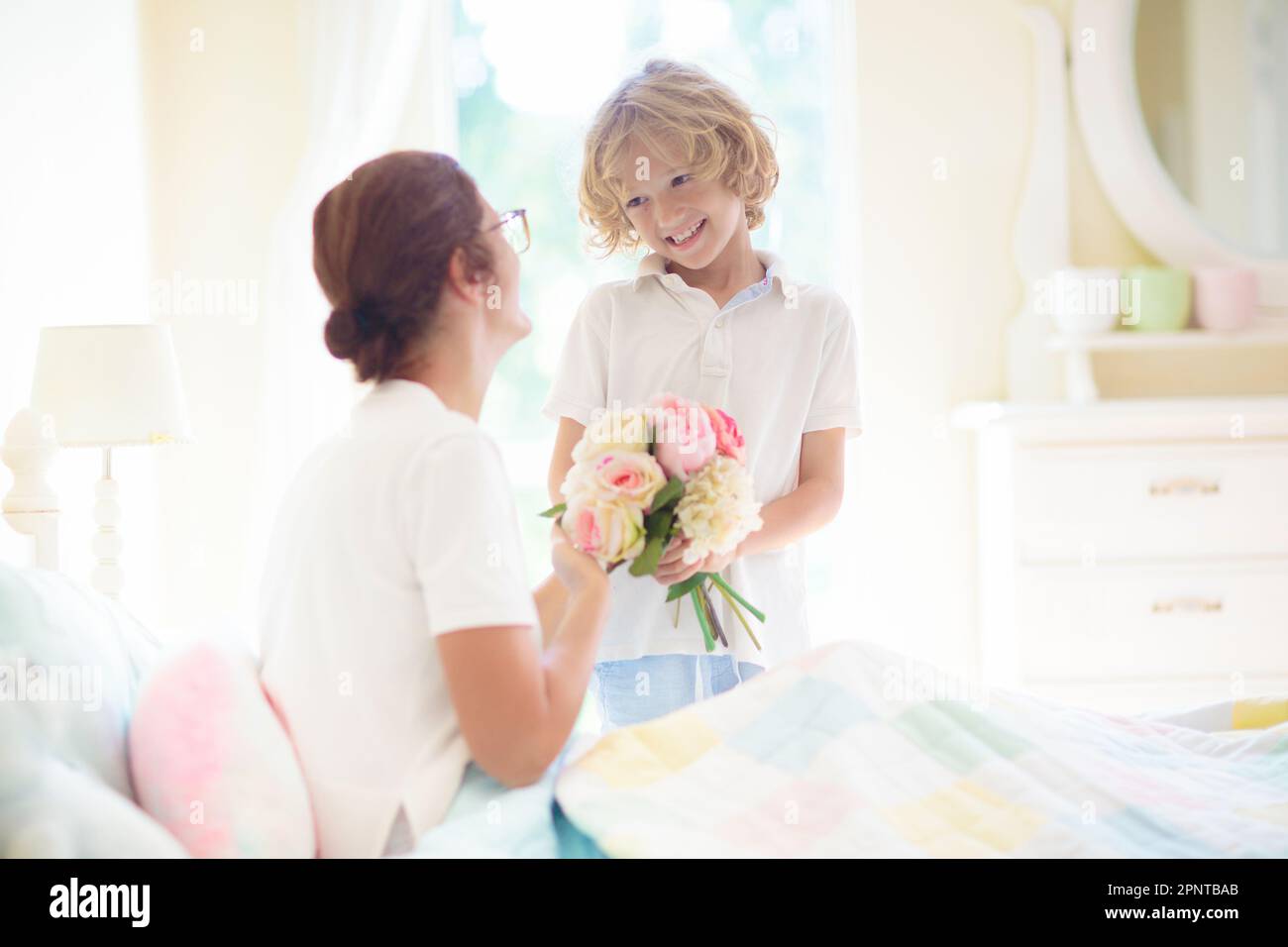 Child giving mom present in bed. Mother’s Day morning gift. Little boy ...