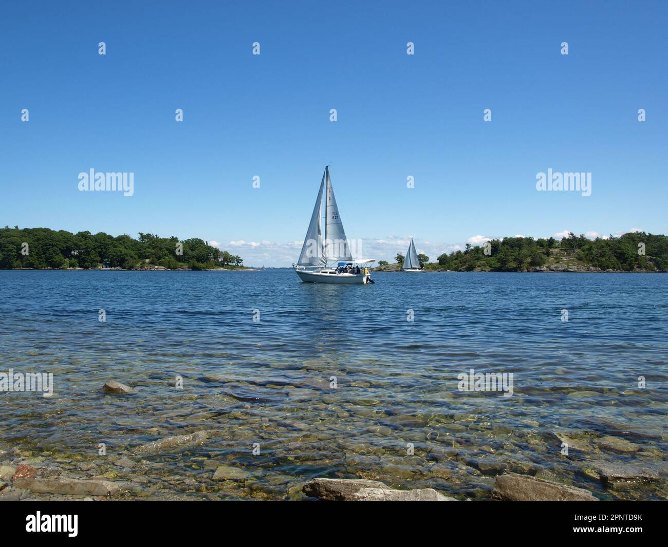White sailed boat on lake flanked by two land masses during summer ...