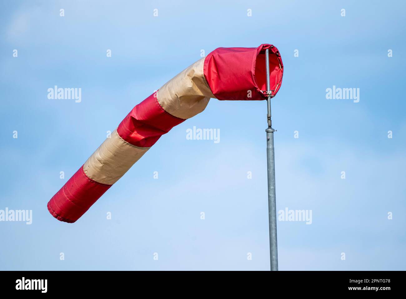 Red and white windsock at an airport, showing wind direction and ...