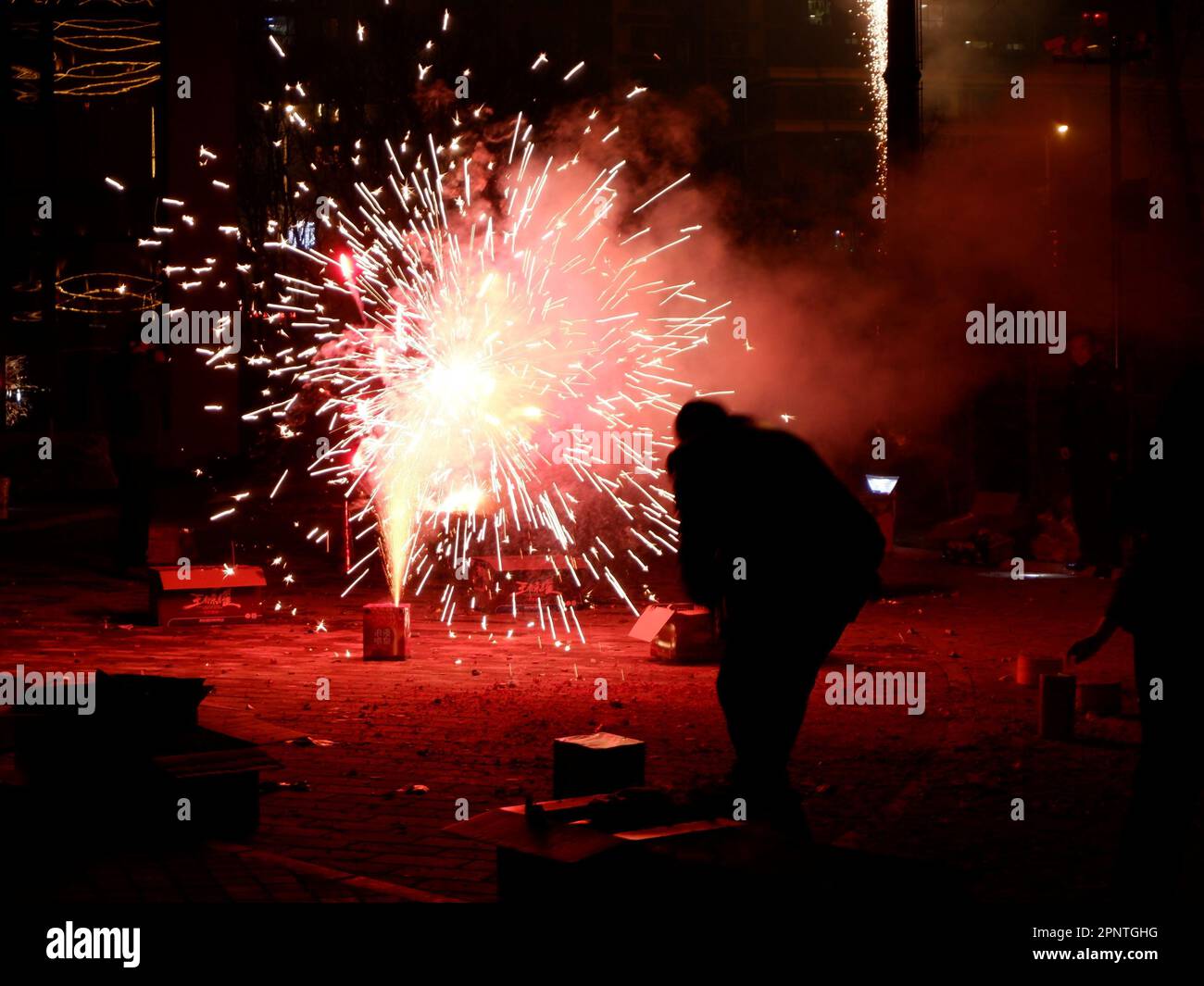 A person standing in front of a bright nighttime scene illuminated by a ...