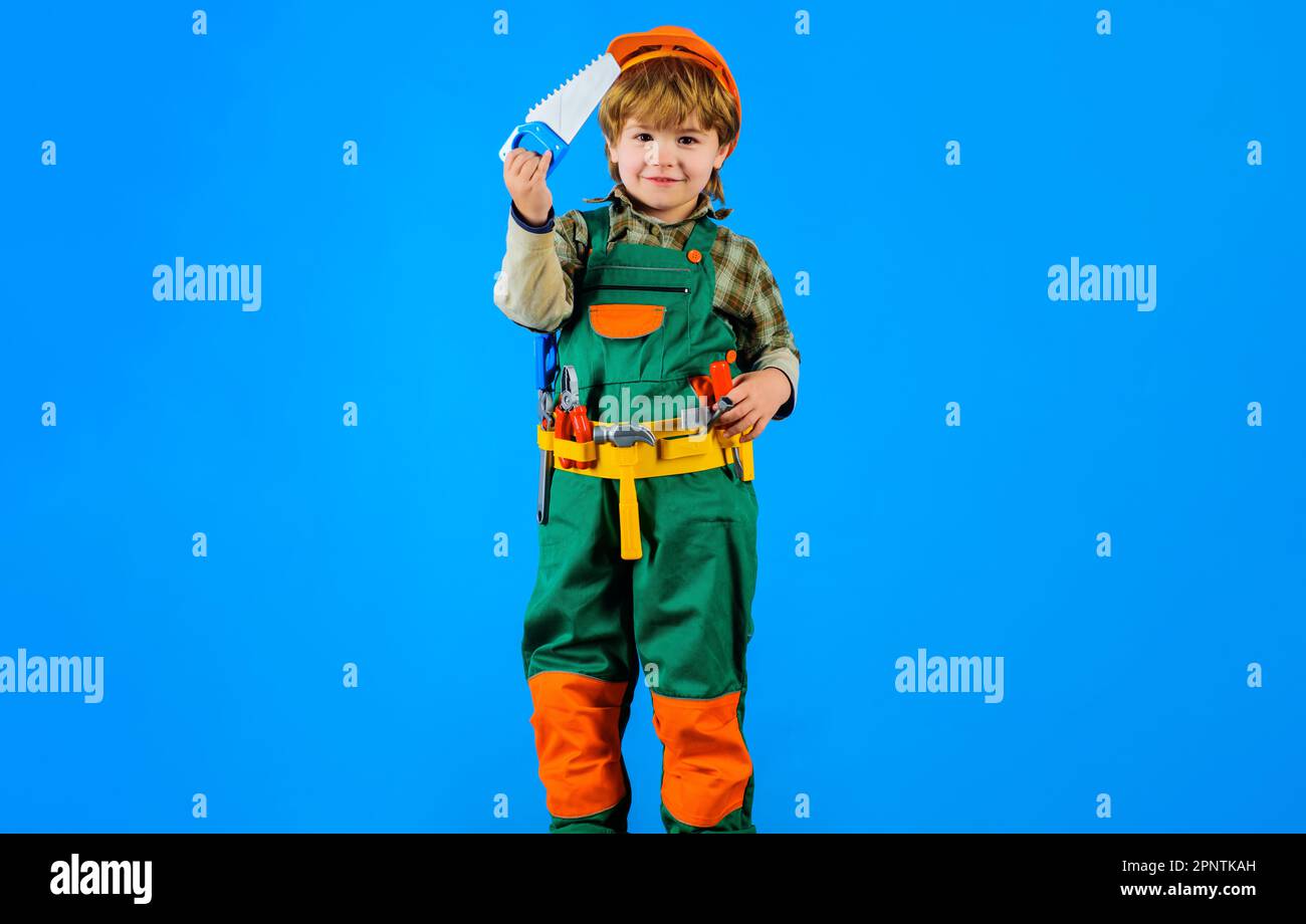 Builder boy in safety helmet and toolbelt with saw. Child in builder ...