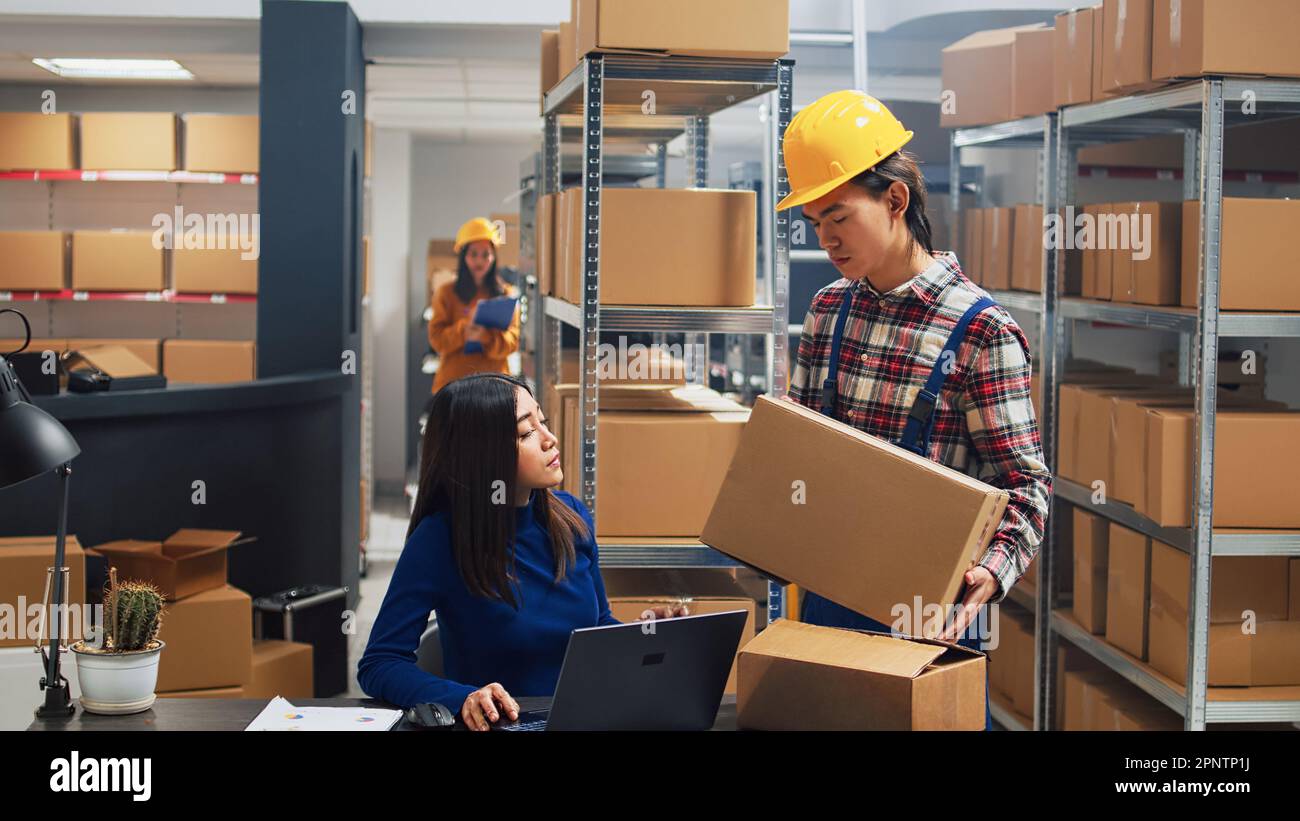 Young man organizing products boxes on racks, doing quality control ...