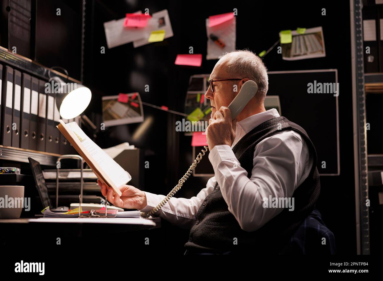 Private detective talking at landline phone with remote inspector ...