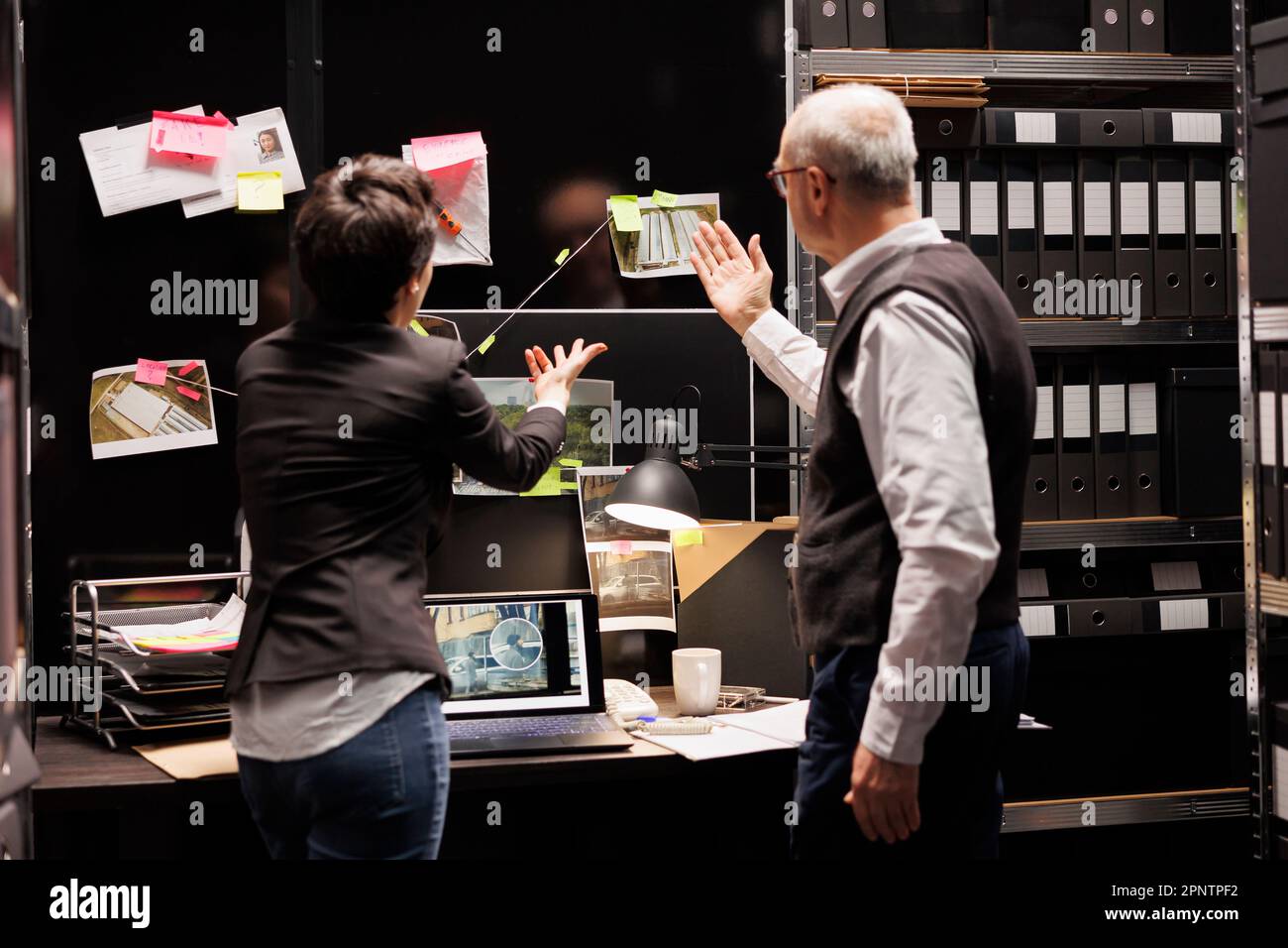 Police officers analyzing board with crime scene evidence, working ...