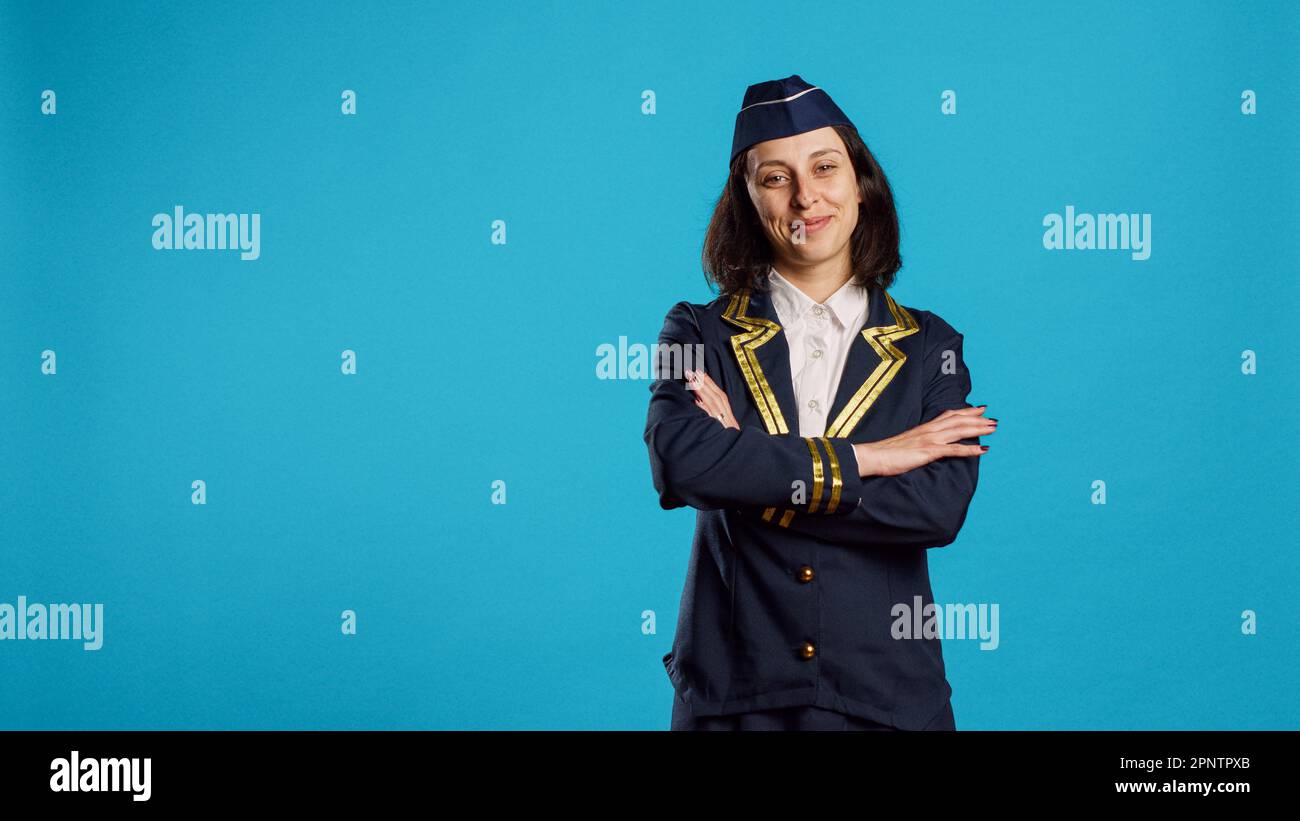 Smiling young woman working as air hostess, wearing flying uniform and ...