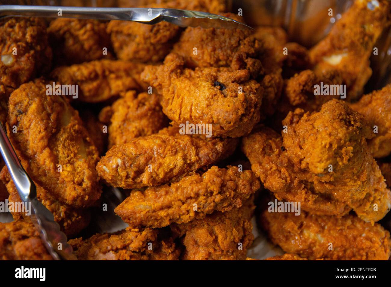 Fried Chicken Wings with Tongs ready to be served Stock Photo - Alamy