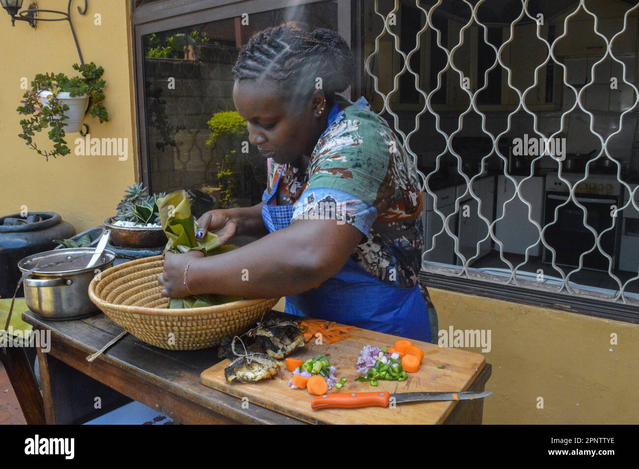 Judith Asiimwe wraps smoked banana leaves around fish with groundnut ...