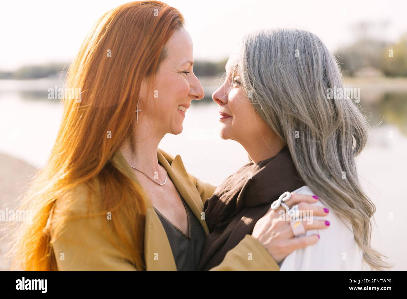 Grown-up daughter and gray-haired beautiful elderly mother looking at ...