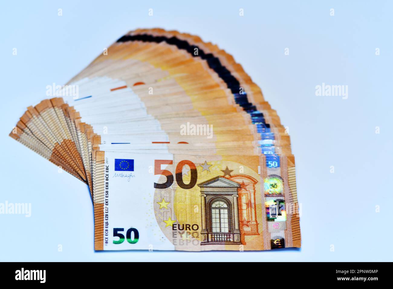 Concept of many euros: a pile of rolled 50-euro bills lying on a white ...