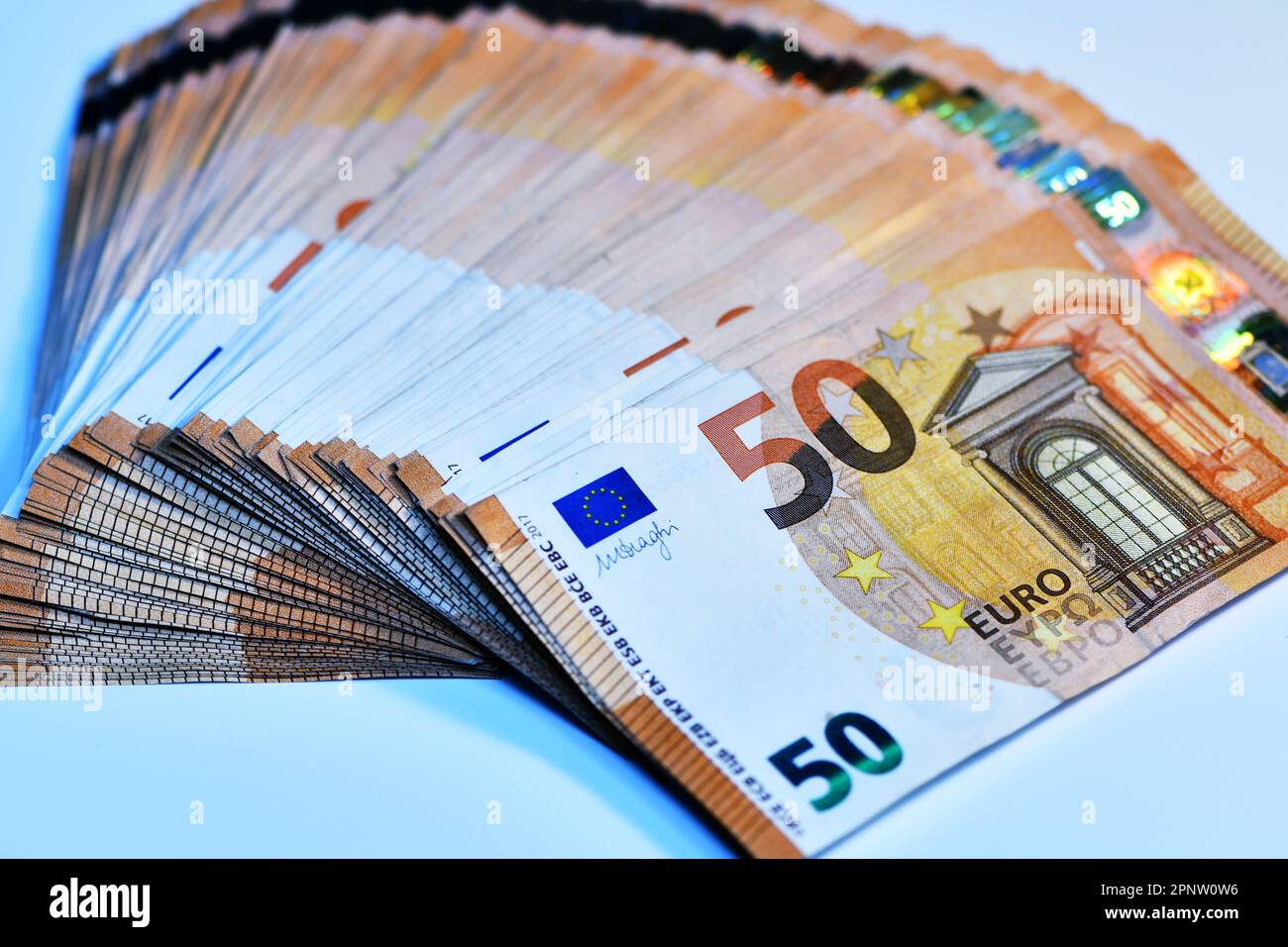 Concept of many euros: a pile of rolled 50-euro bills lying on a white ...