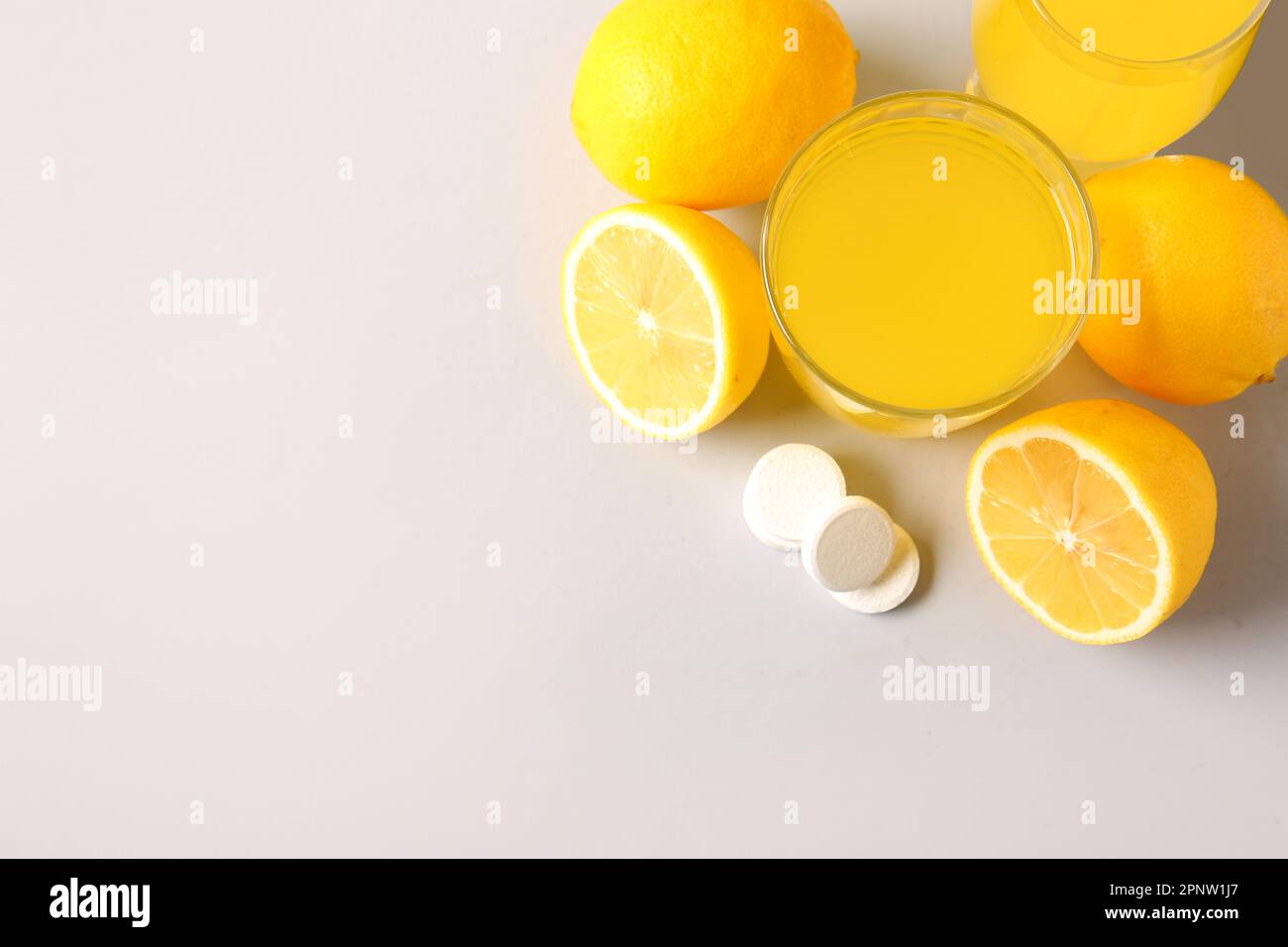 Glass of vitamin C effervescent tablet dissolved in water and lemons on ...
