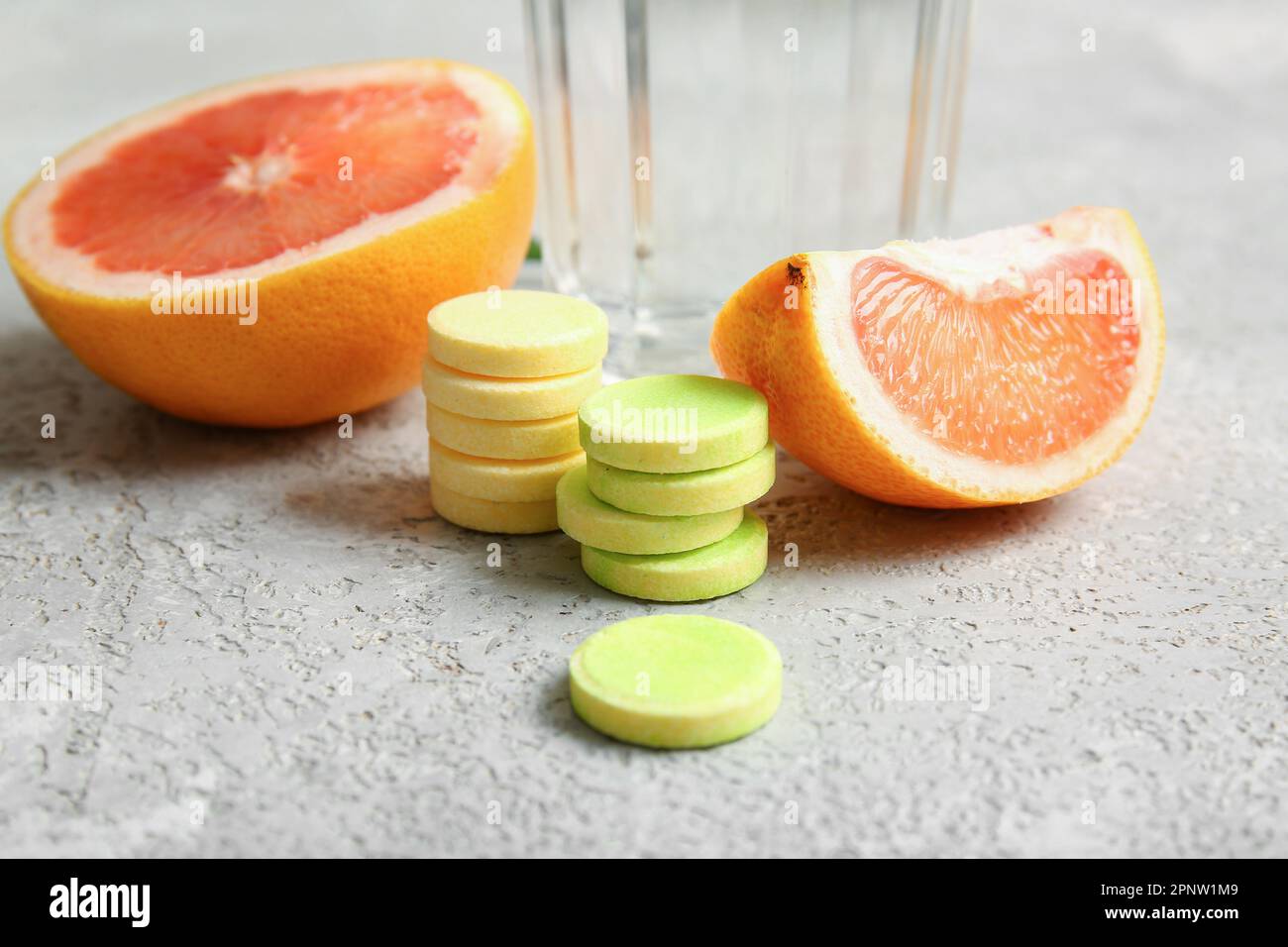 Vitamin C effervescent tablets and grapefruit pieces on grey grunge ...