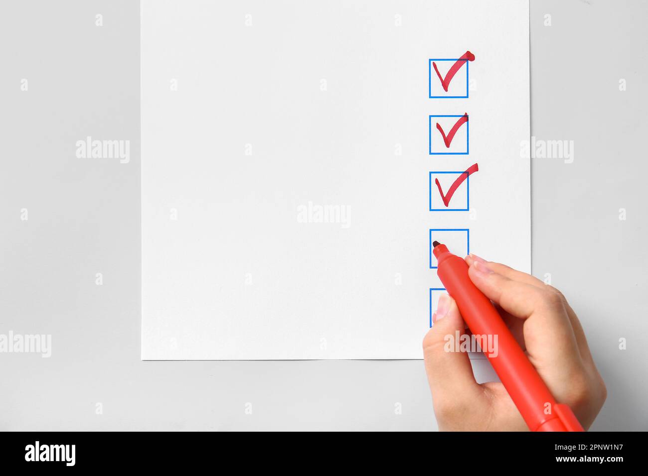 Woman marking on checklist box, top view Stock Photo - Alamy
