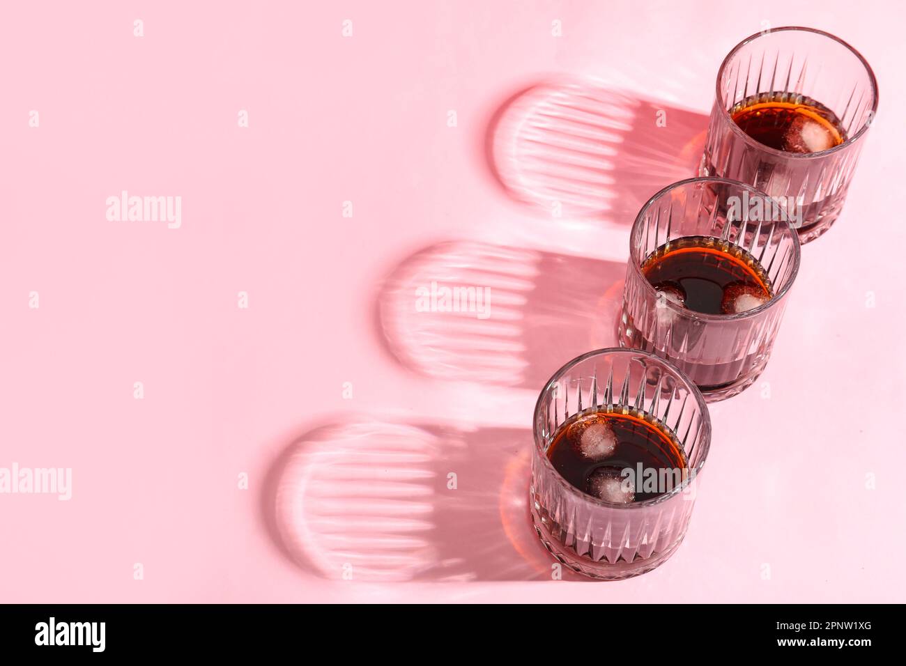 Glasses of rum with ice cubes on pink background Stock Photo - Alamy