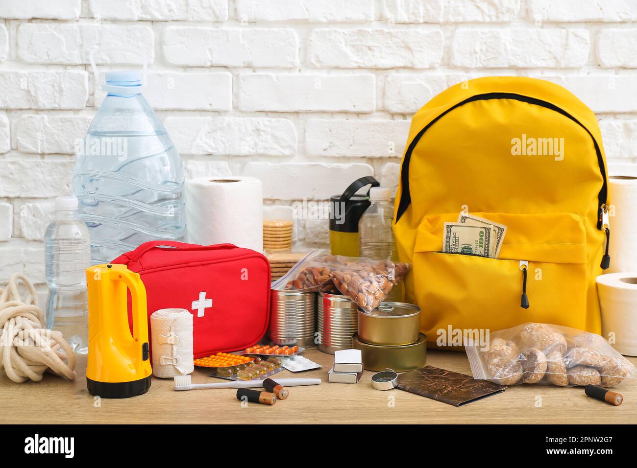 Necessities for emergency bag on wooden table near white brick wall ...