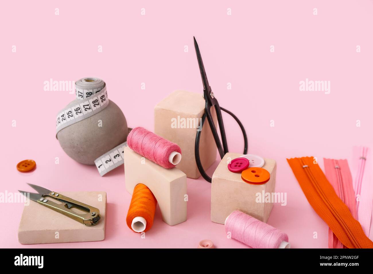 Podiums with tailor's supplies on pink background Stock Photo - Alamy